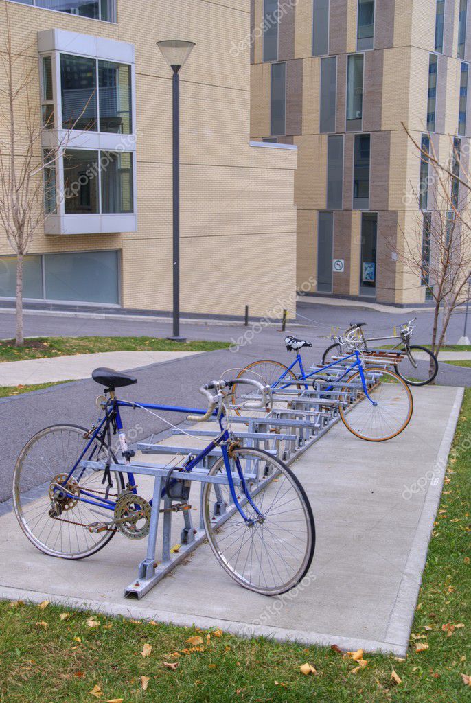 Bicycles parked and locked in bike rack in front of buildings. — Stock ...
